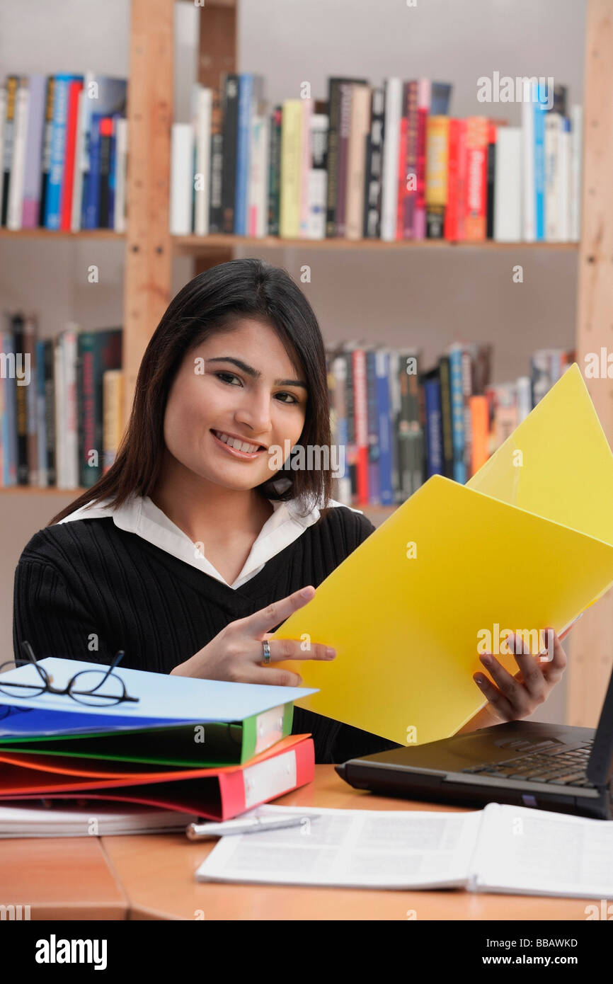 Woman in library, holding yellow folder Stock Photo - Alamy