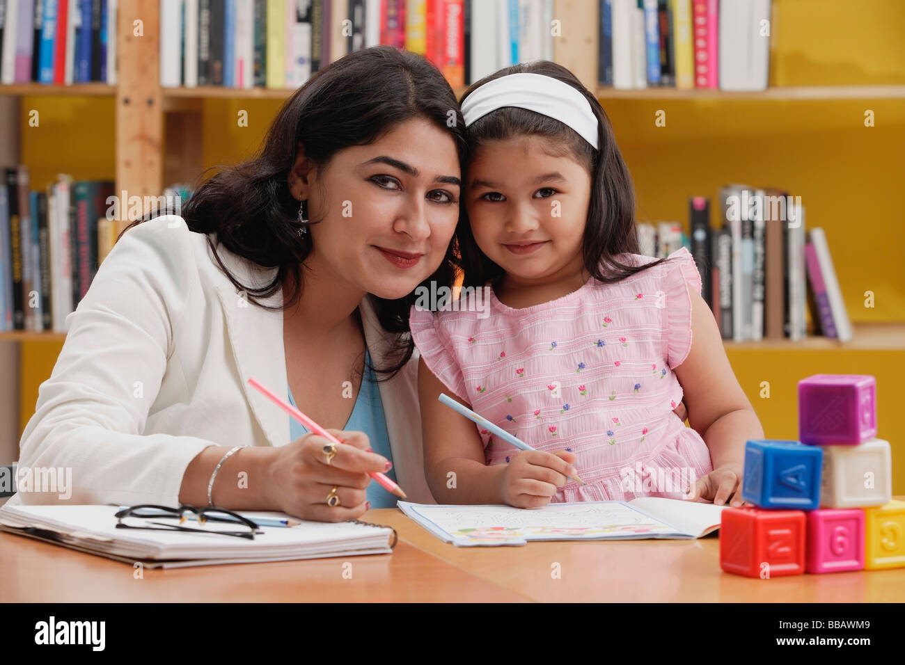 Woman and girl with books, looking at camera Stock Photo - Alamy