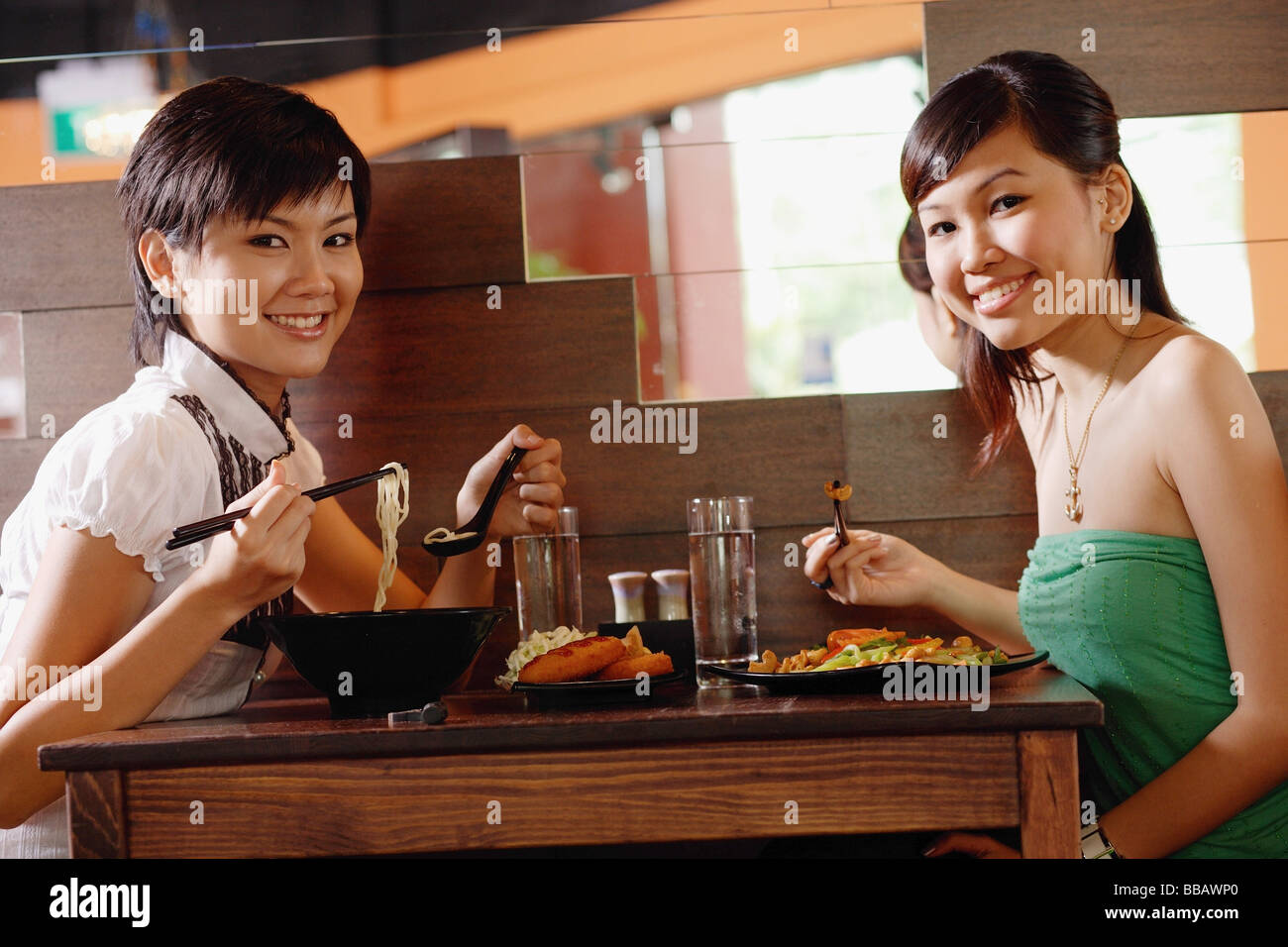 Two young women sitting at table in restaurant, smiling at camera Stock ...
