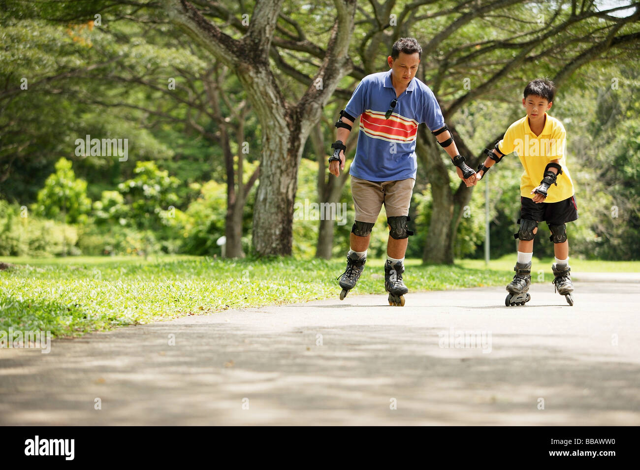 Father and son in-line skating in park Stock Photo - Alamy