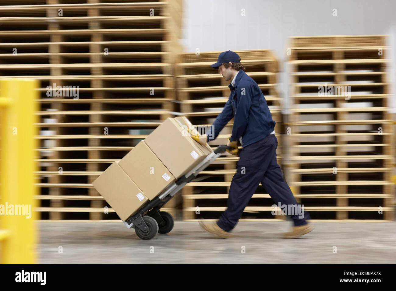 Worker pushing trolley in warehouse Stock Photo - Alamy
