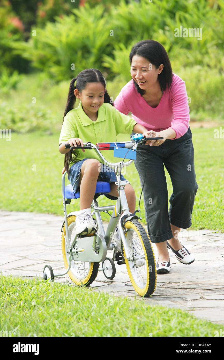 Daughter cycling, mother guiding her Stock Photo - Alamy
