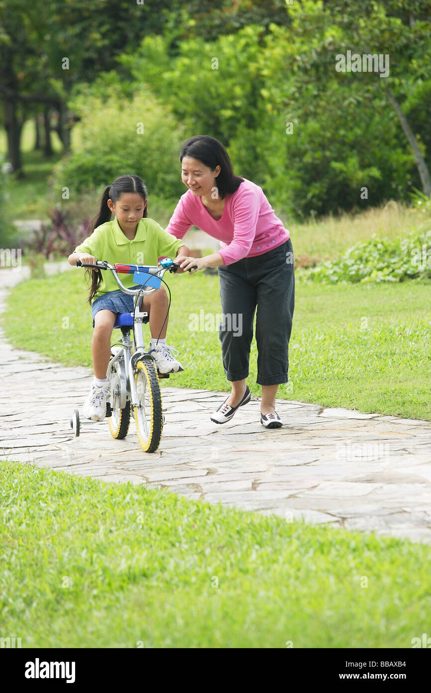Mother guiding daughter on bicycle Stock Photo - Alamy