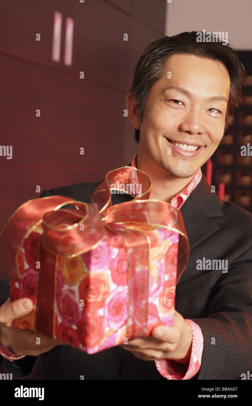 Man holding wrapped gift, smiling Stock Photo - Alamy