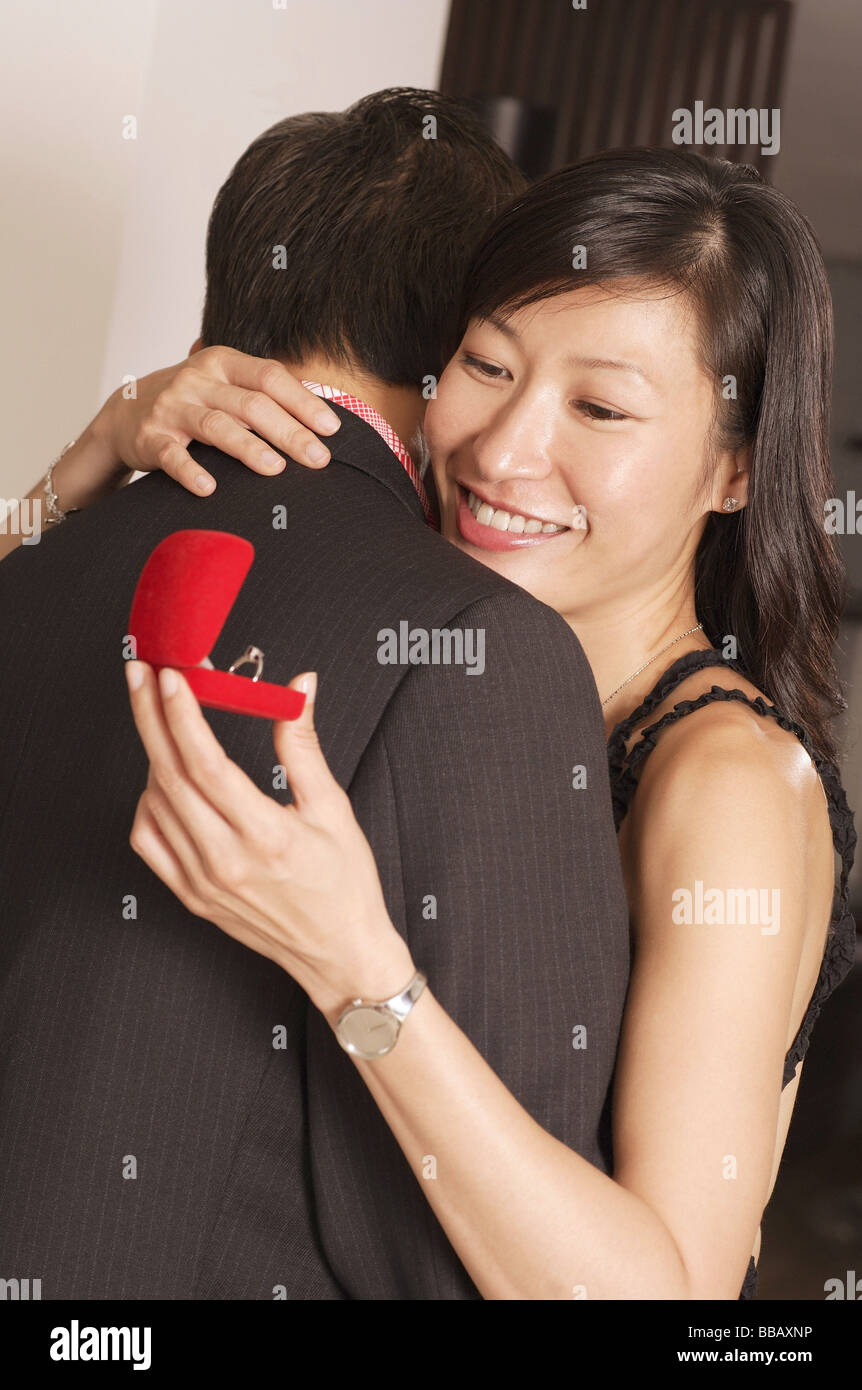 Couple hugging, woman looking at ring in box Stock Photo - Alamy