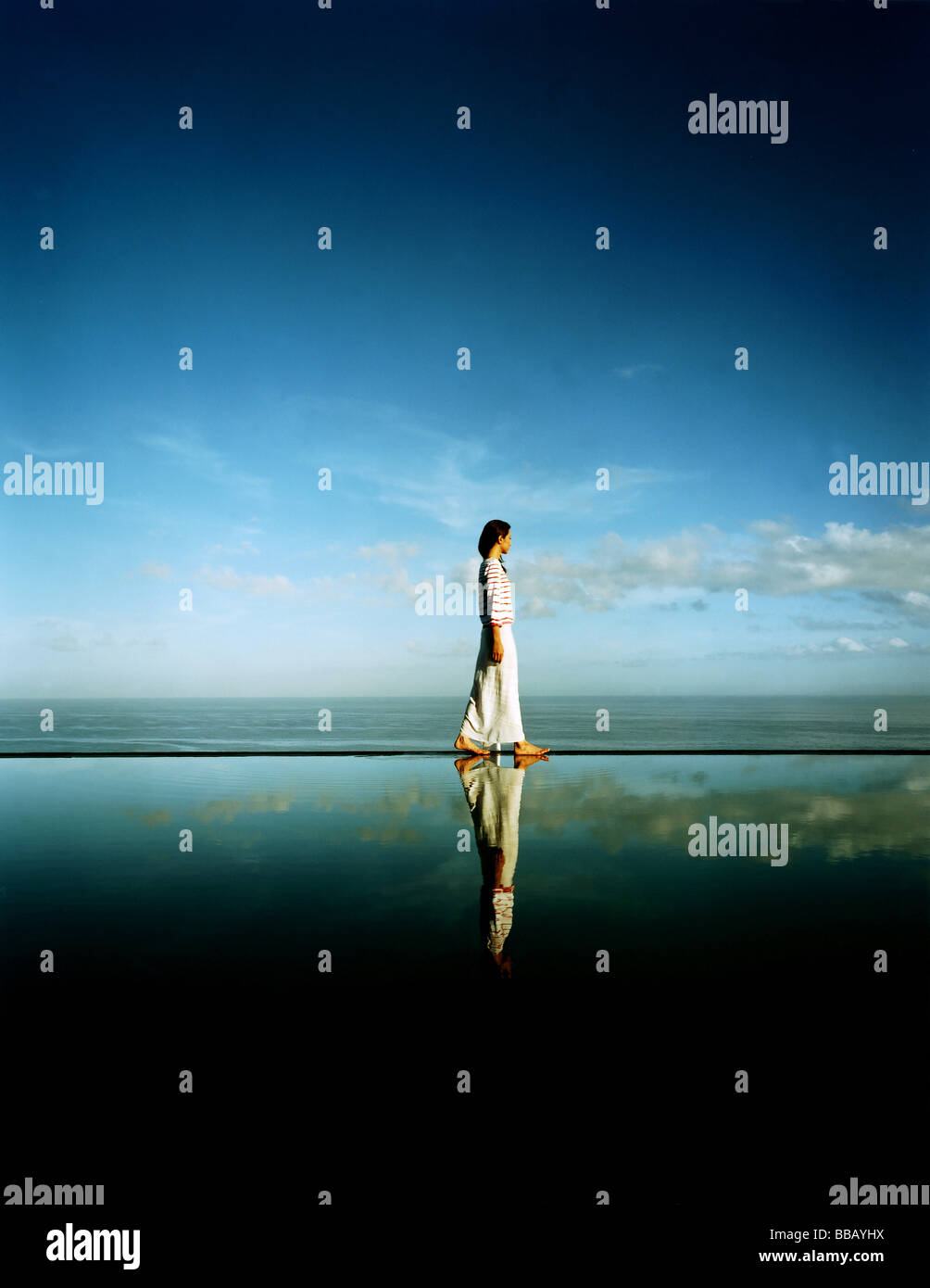 Asian female walking along edge of horizon pool Stock Photo - Alamy