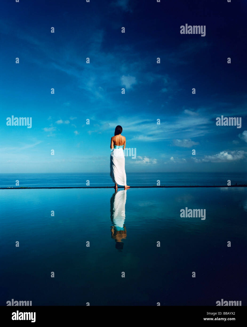 Asian female standing along edge of horizon pool Stock Photo - Alamy