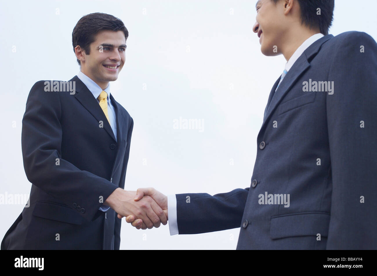 Businessmen shaking hands, low angle view Stock Photo - Alamy