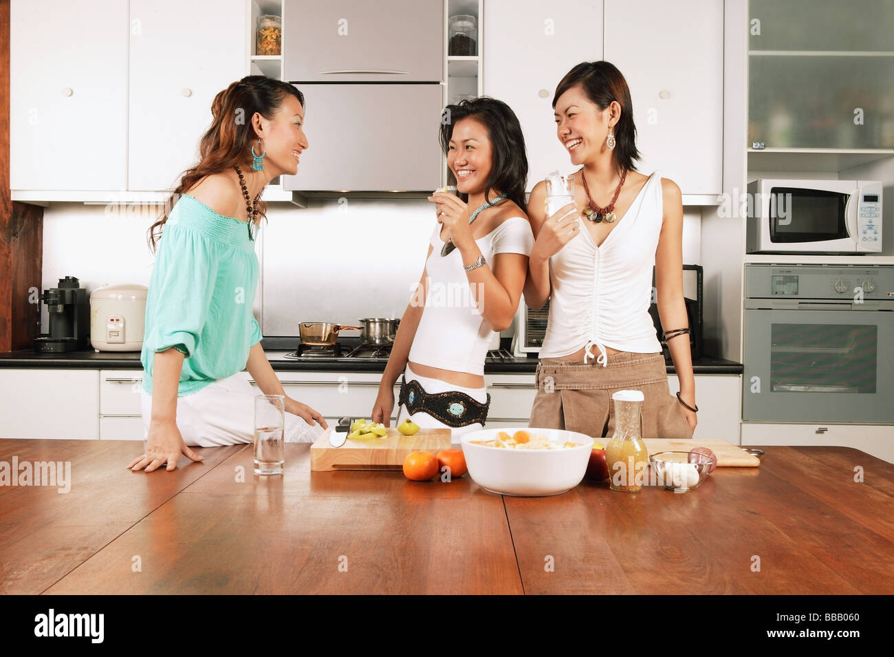 Three women standing in kitchen, laughing Stock Photo - Alamy