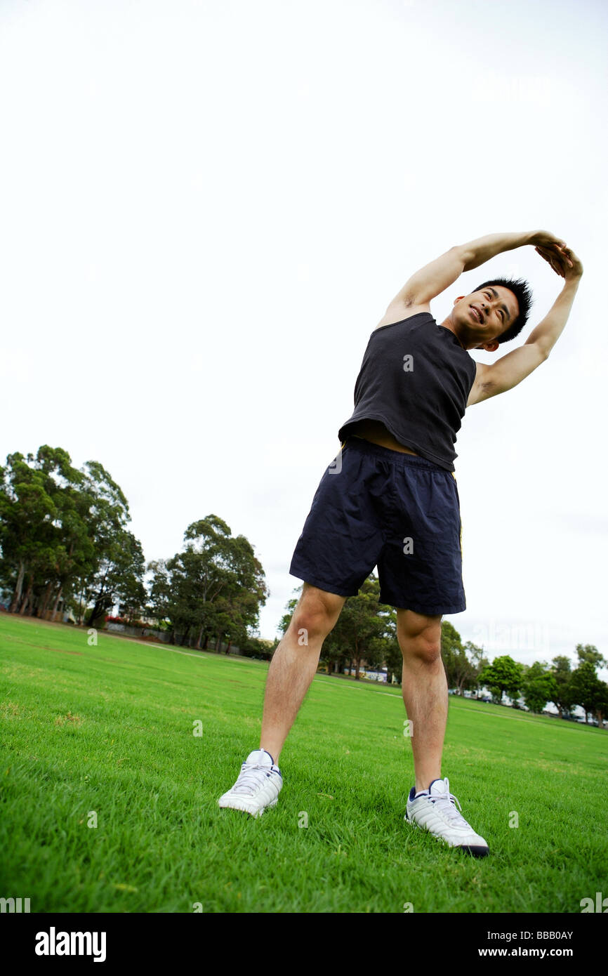 Man standing on grass, stretching Stock Photo - Alamy