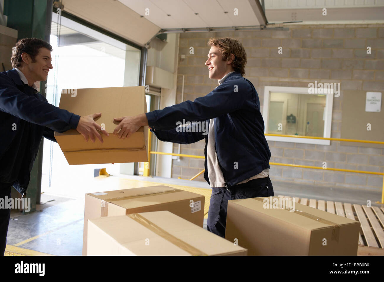 Two workers passing box Stock Photo - Alamy