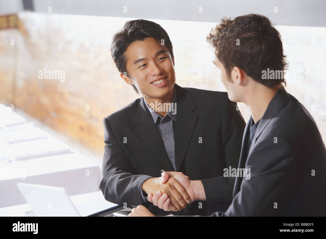 Two men sitting, shaking hands Stock Photo - Alamy