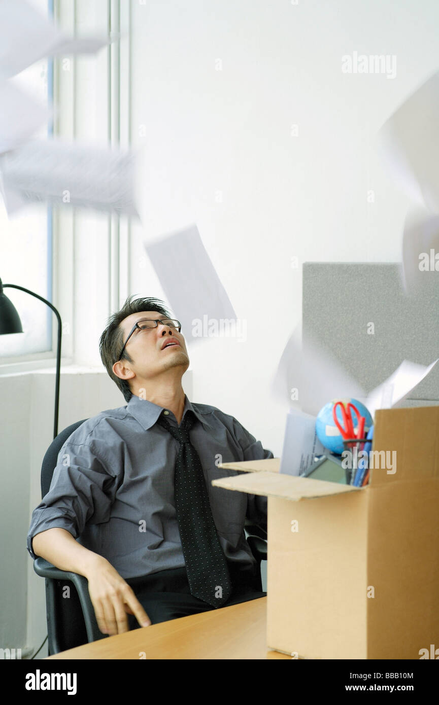 Businessman sitting in office, papers falling around him Stock Photo ...