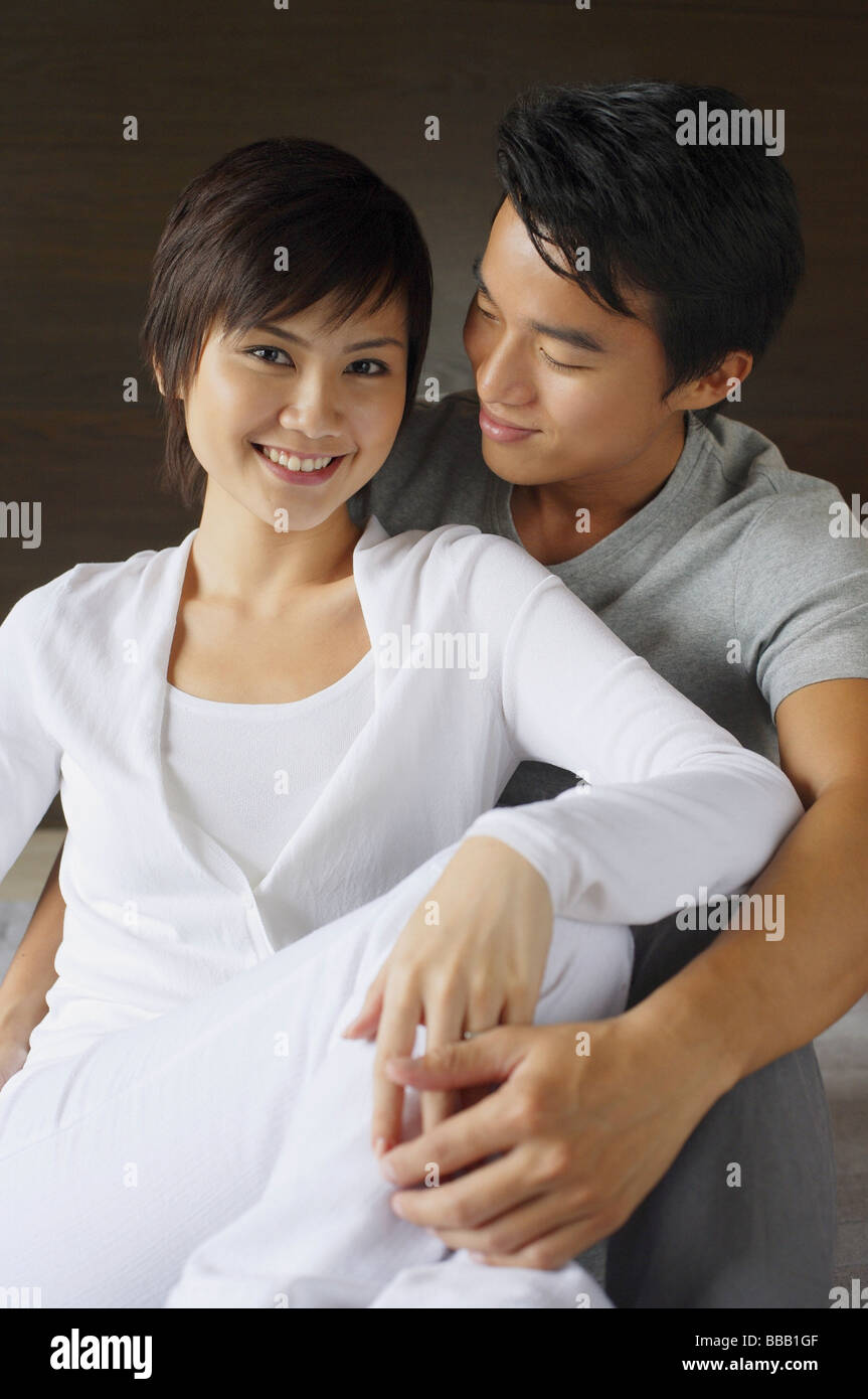 Couple sitting side by side, embracing, woman smiling at camera Stock ...