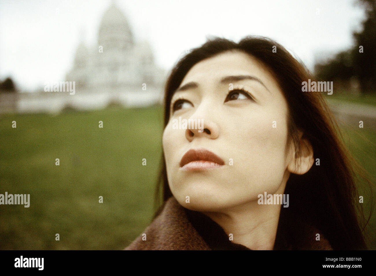 Woman looking up, building and lawn in background Stock Photo - Alamy