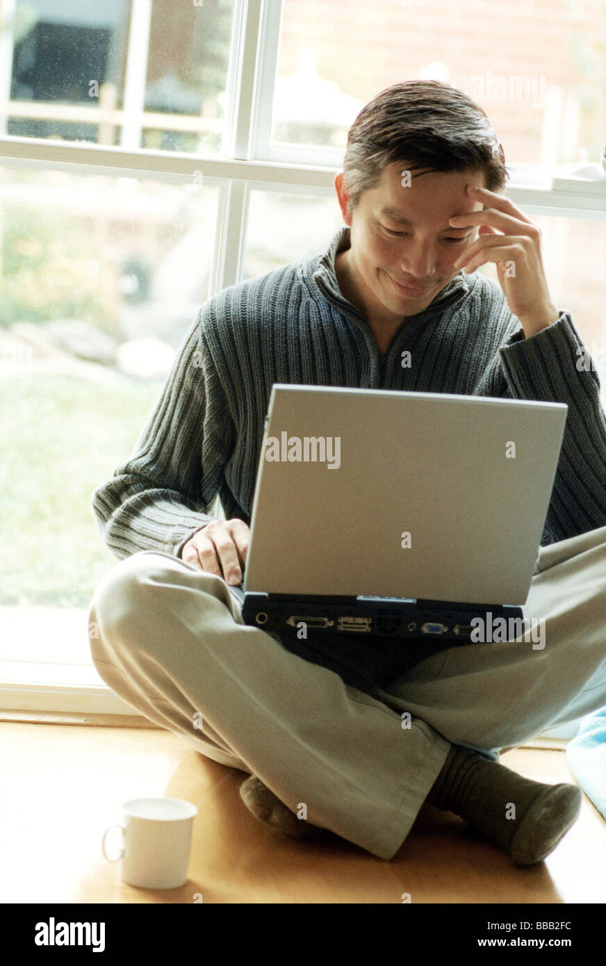 Man sitting cross-legged using laptop Stock Photo - Alamy