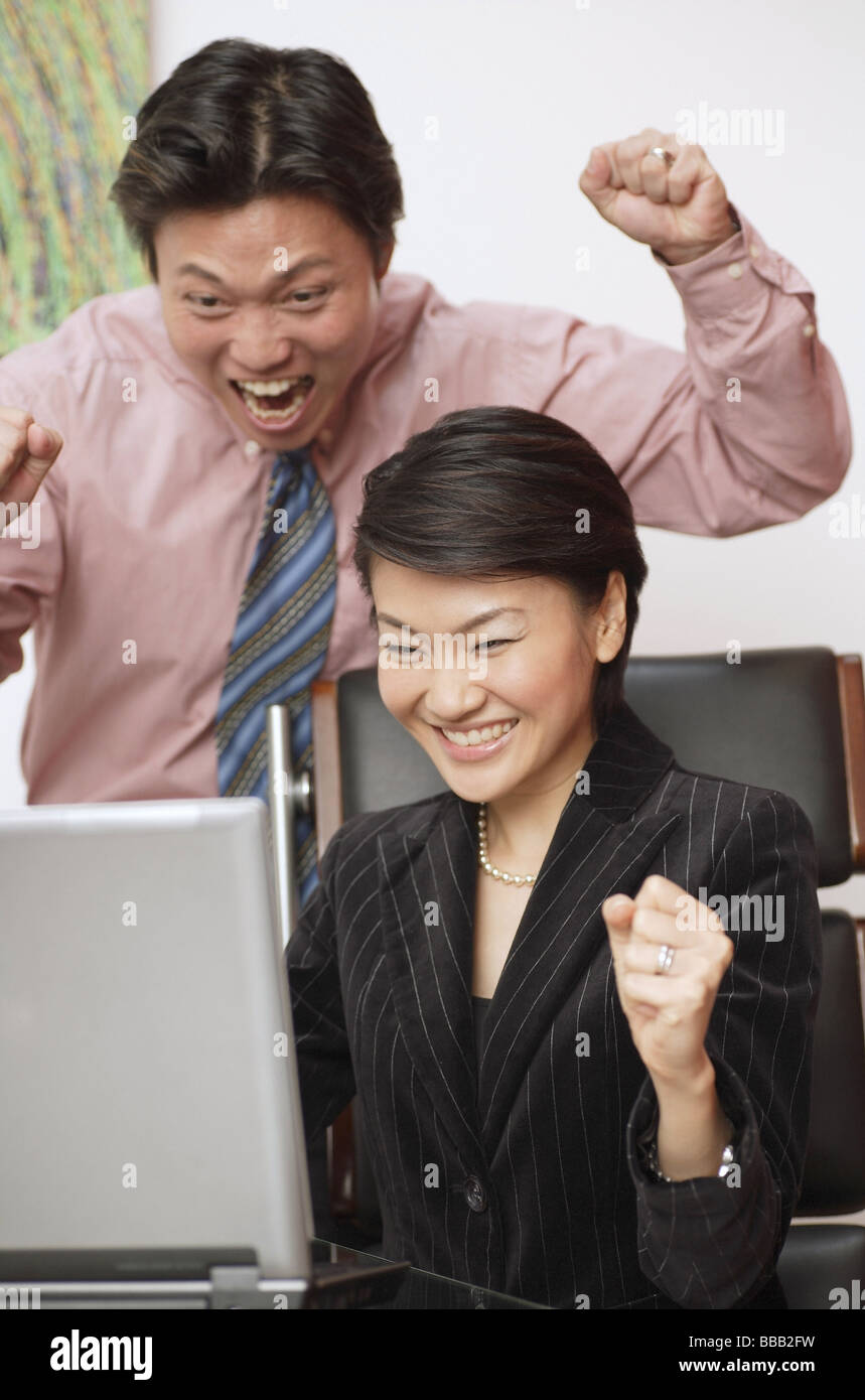 Businesspeople with excited expressions, looking at computer monitor ...
