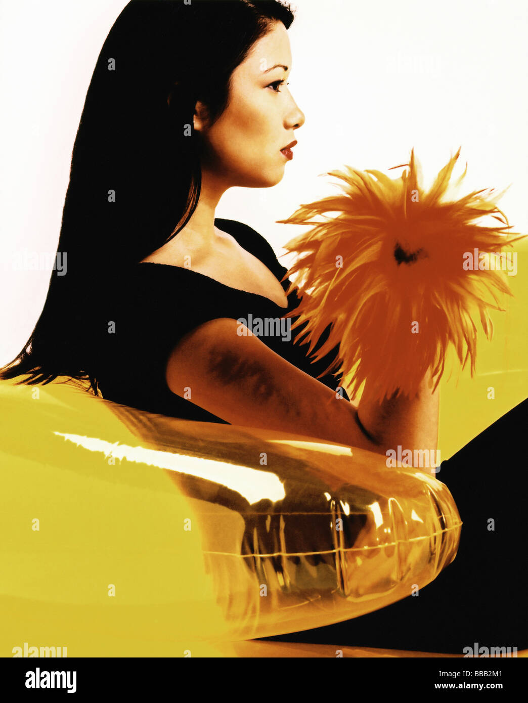 Young woman sitting on yellow inflatable chair, profile Stock Photo - Alamy