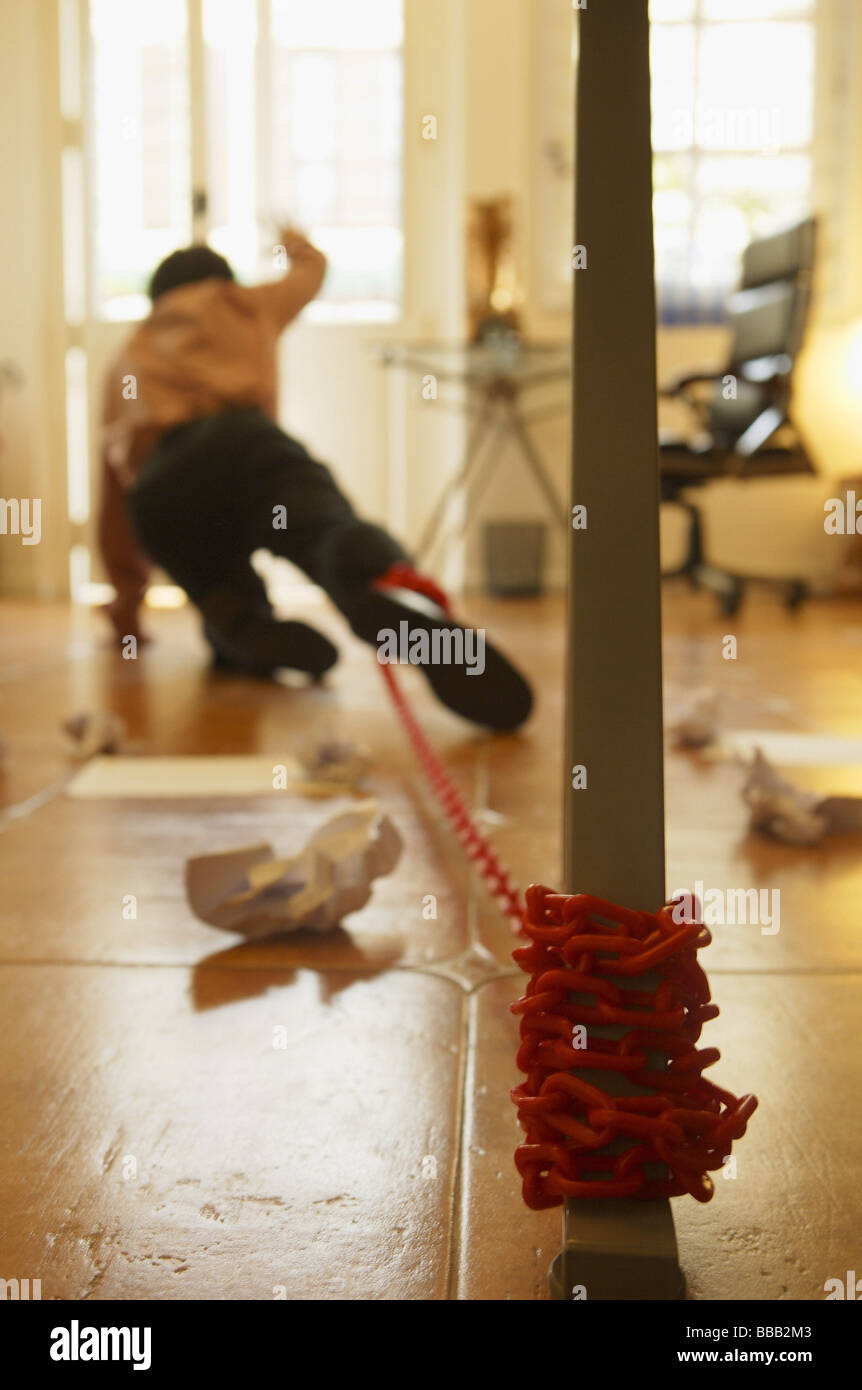 Executive tied to pole by chain, crawling towards door Stock Photo - Alamy