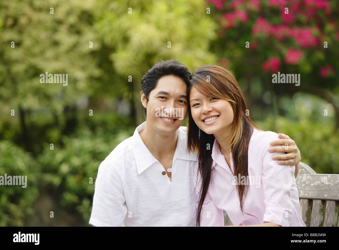 Couple sitting on park bench, smiling at camera Stock Photo - Alamy