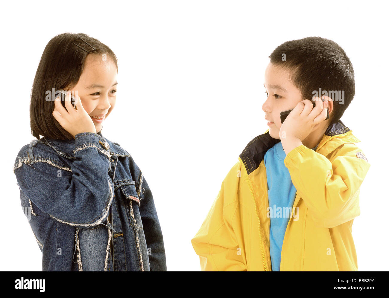 Two children (boy and girl) talking on cellular phones, white ...