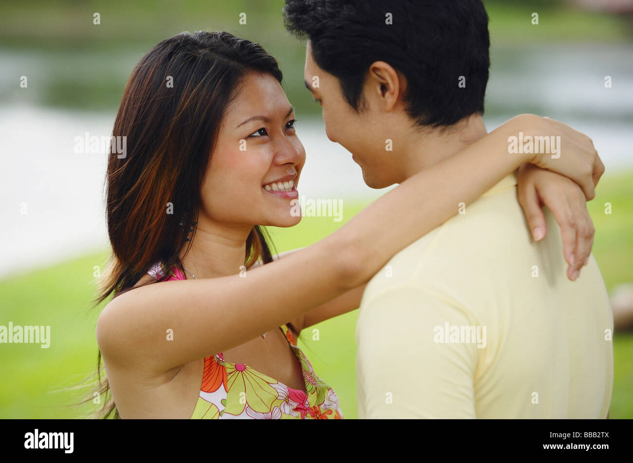 Couple standing face to face, woman with arms around man Stock Photo ...
