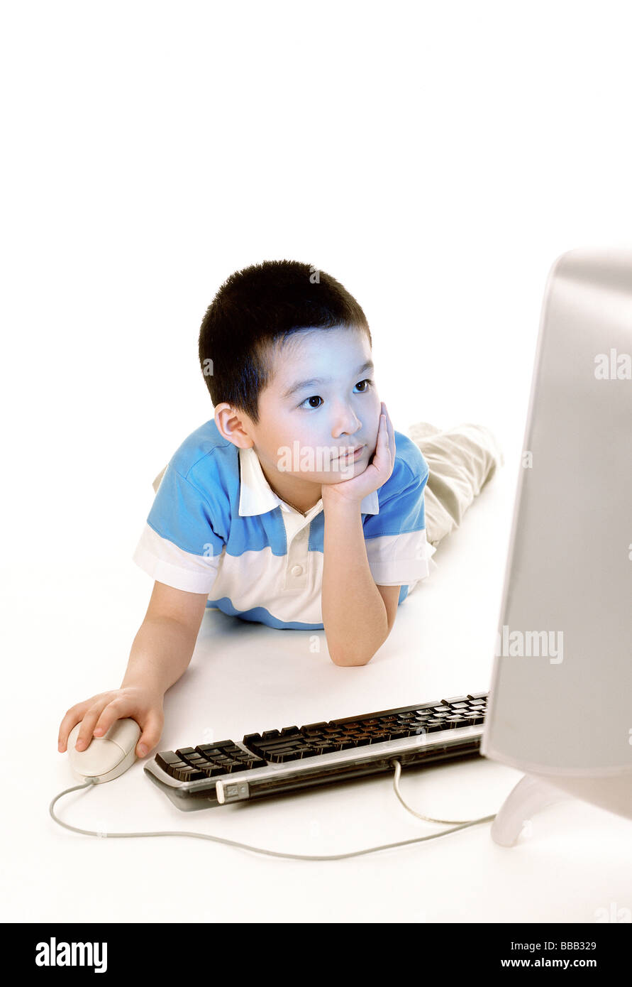 Young boy using desktop computer, looking at monitor, white background ...