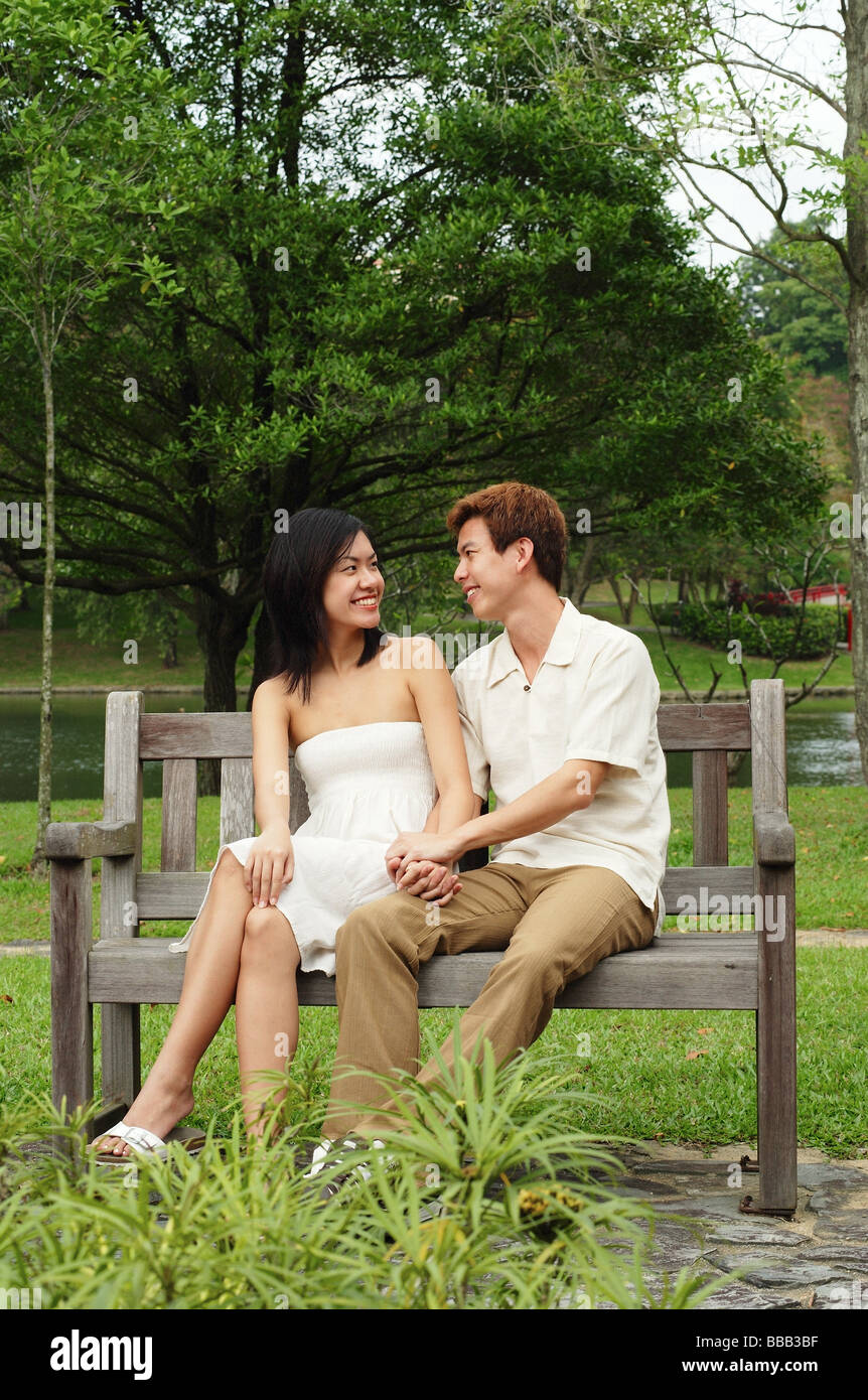 Couple sitting on park bench Stock Photo - Alamy