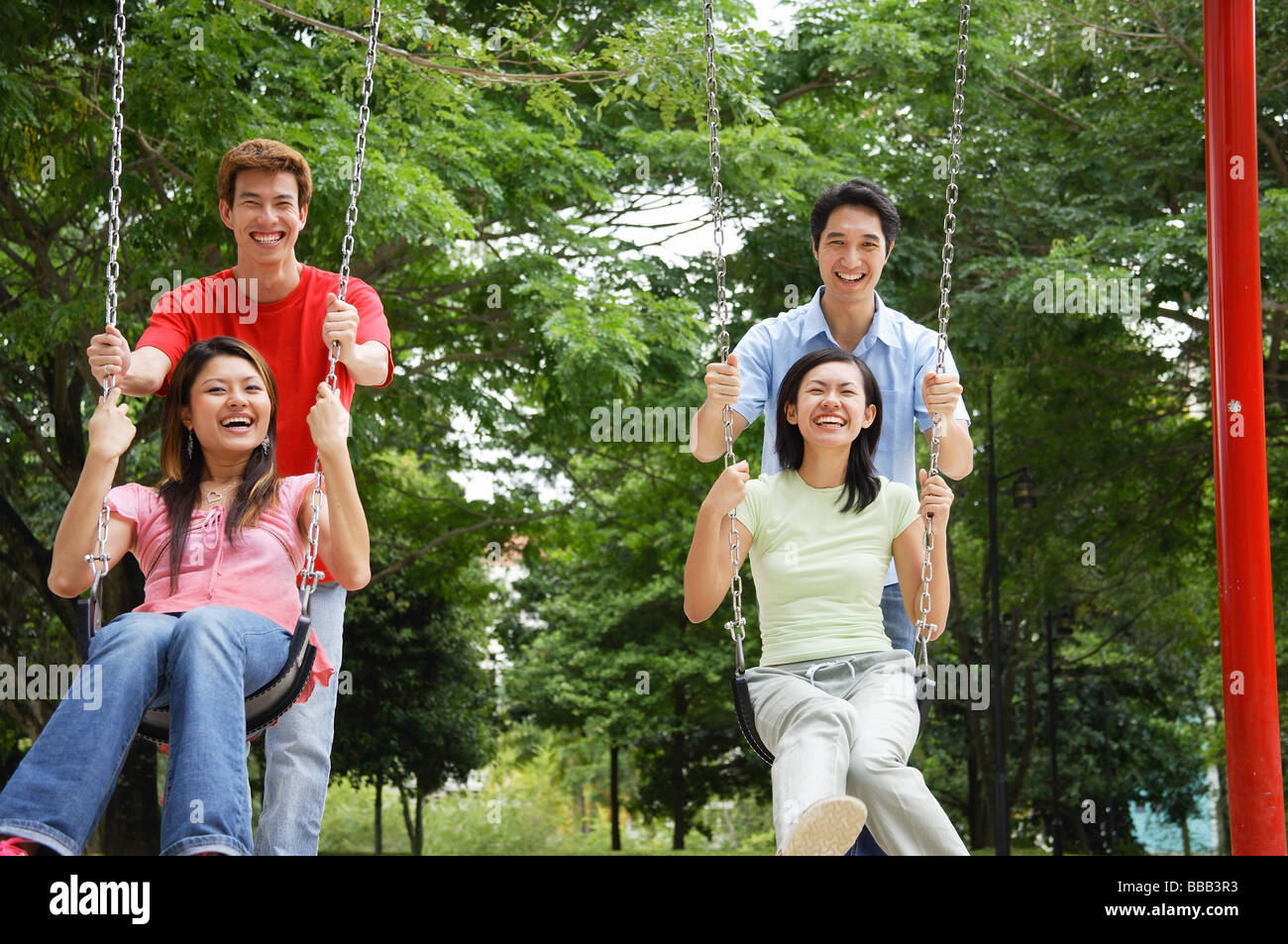 Couples in playground, women on swings, men pushing them Stock Photo ...
