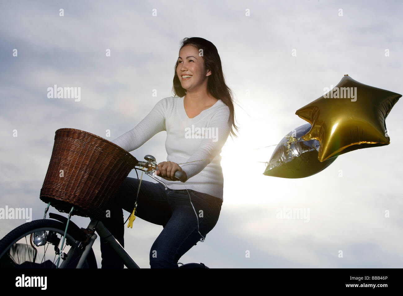Young woman riding bike with star-shaped balloons Stock Photo - Alamy