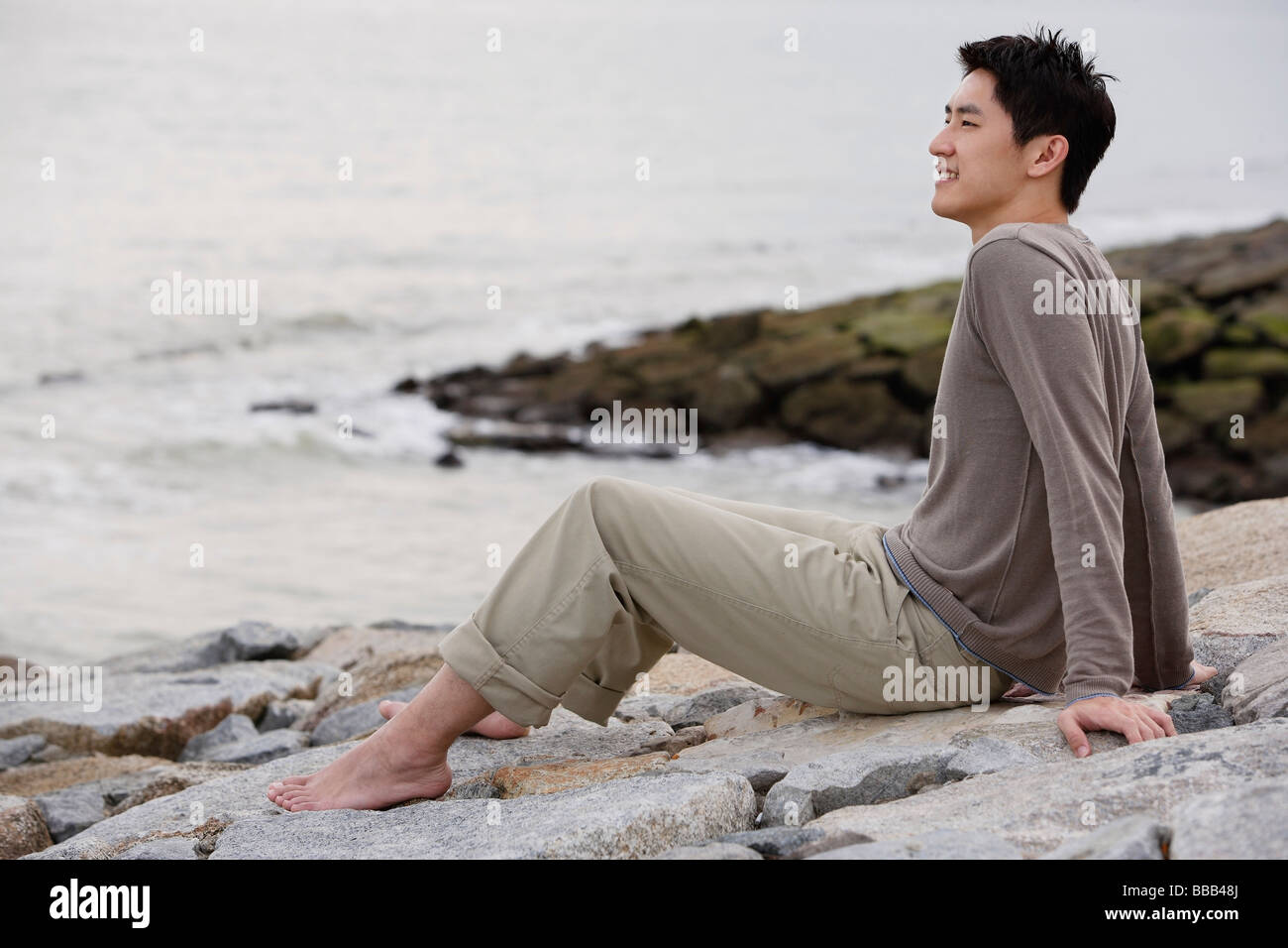 Man sitting on sea shore Stock Photo - Alamy