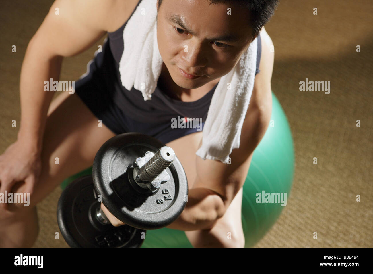 Man sitting on fitness ball, lifting dumbbell Stock Photo - Alamy