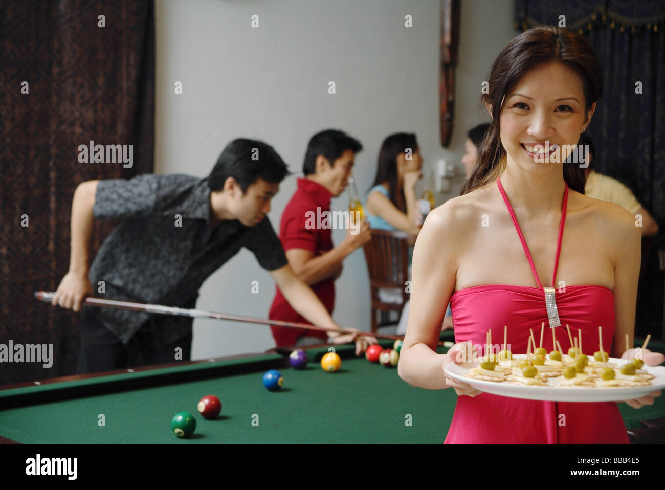 Party host with plate of appetizers, smiling at camera, people in the ...
