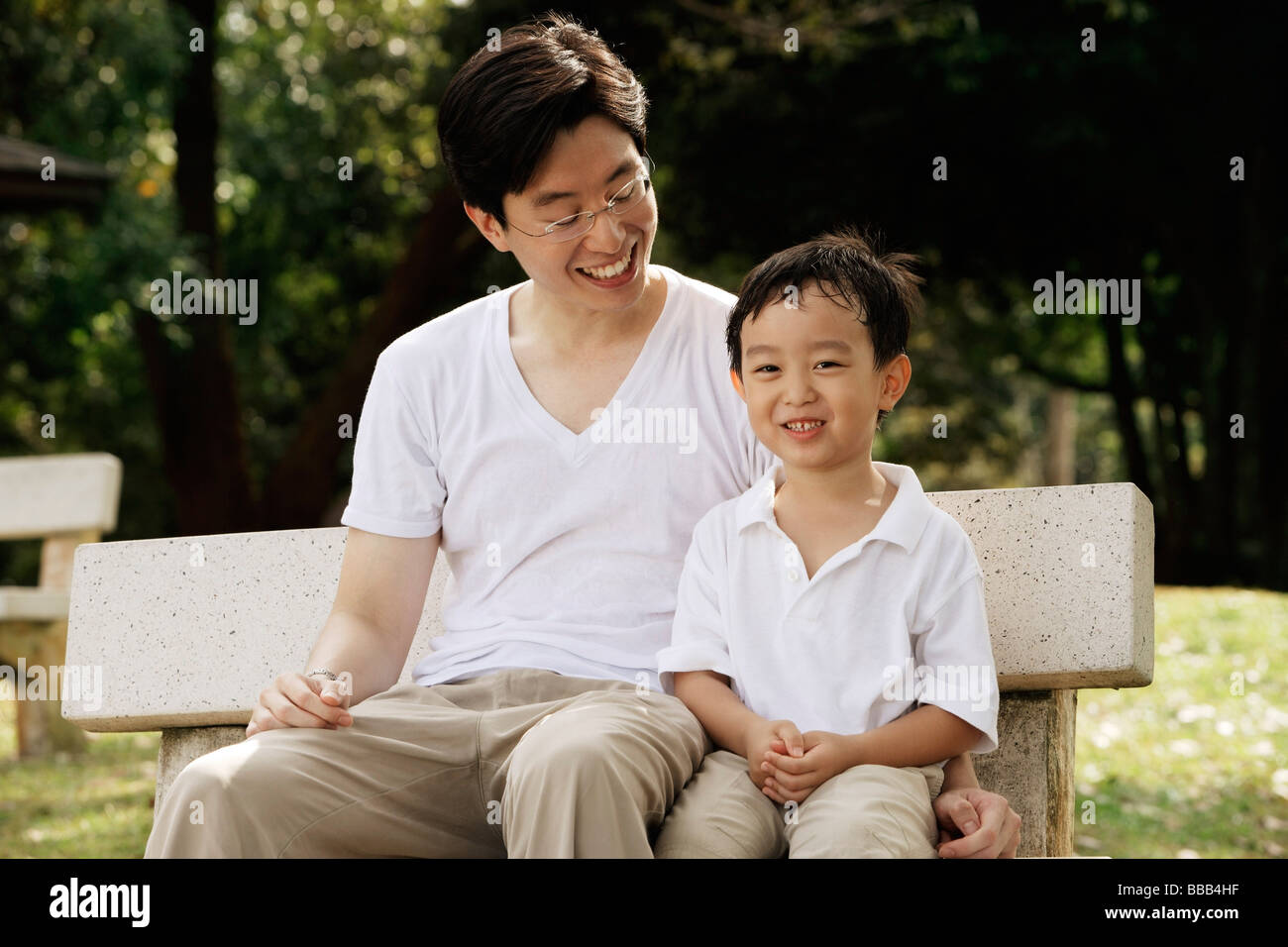 Father and son sitting on park bench Stock Photo - Alamy