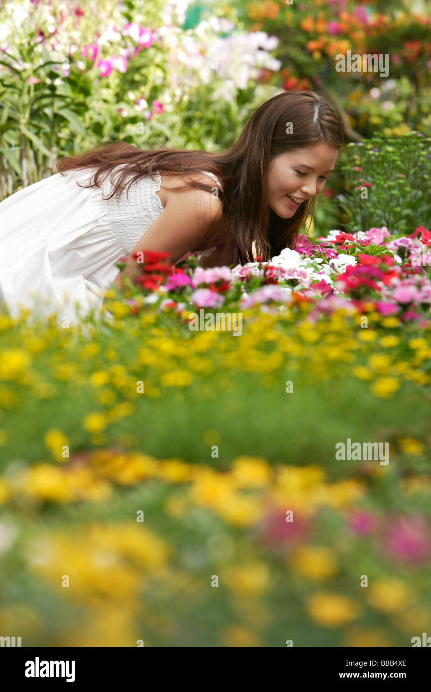 Young woman leaning over to smell the flowers Stock Photo - Alamy