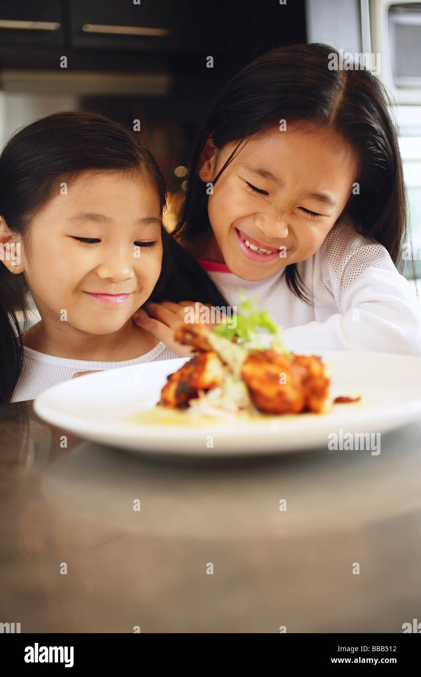 Two children looking at a plate of food, smiling Stock Photo - Alamy