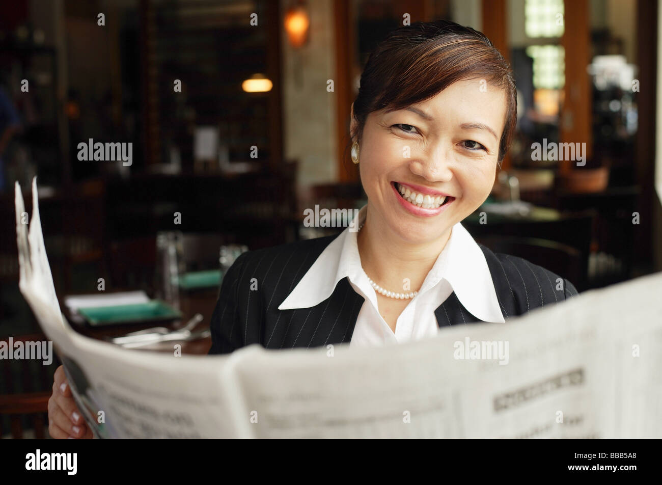 Businesswoman holding newspaper, smiling Stock Photo - Alamy