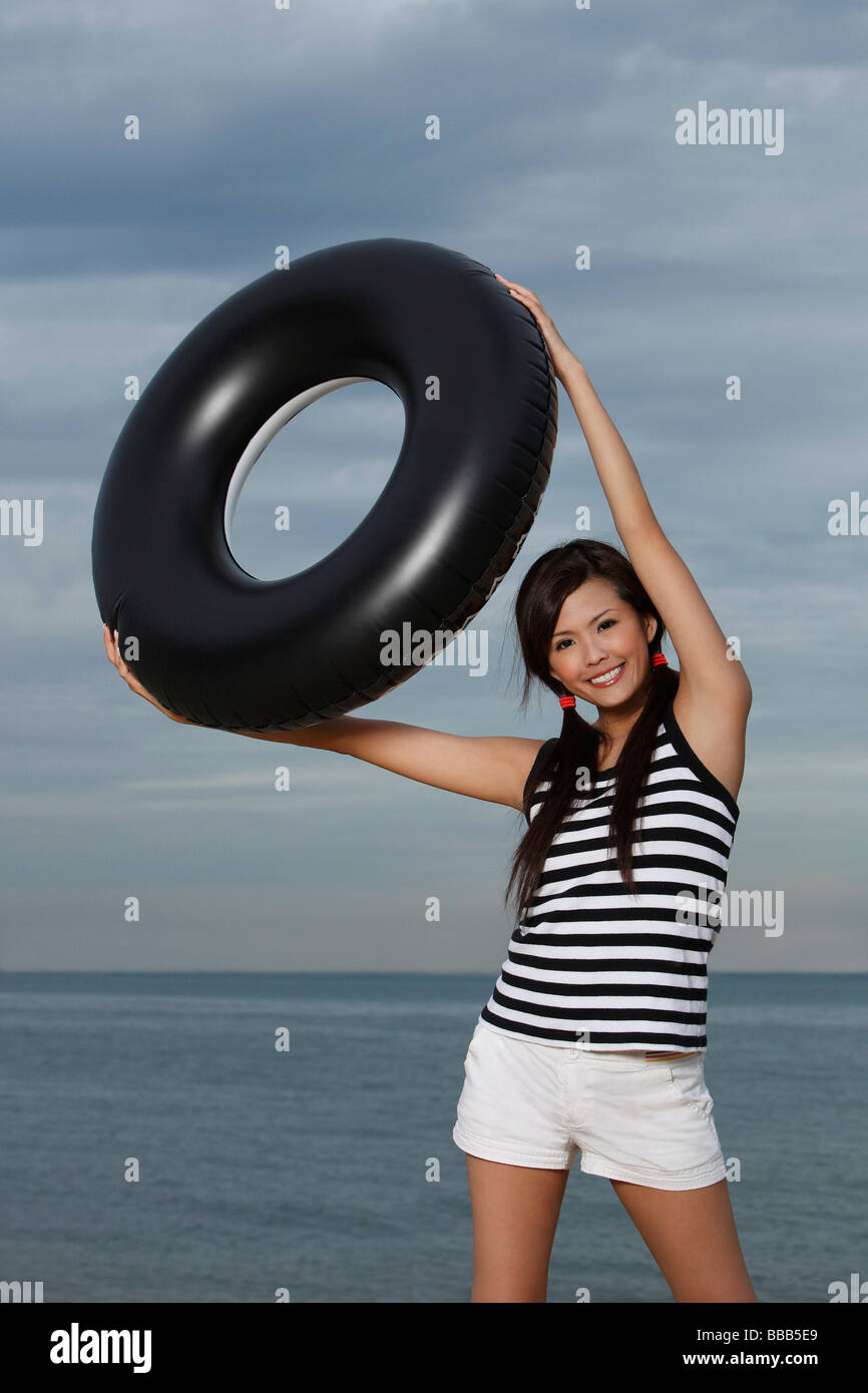 Young woman smiling and holding up inner tube Stock Photo - Alamy
