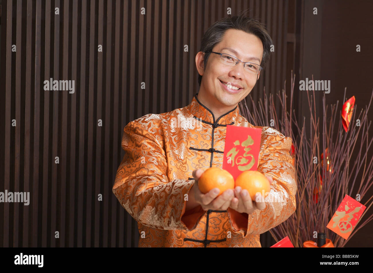 Man in traditional Chinese clothing holding oranges Stock Photo - Alamy