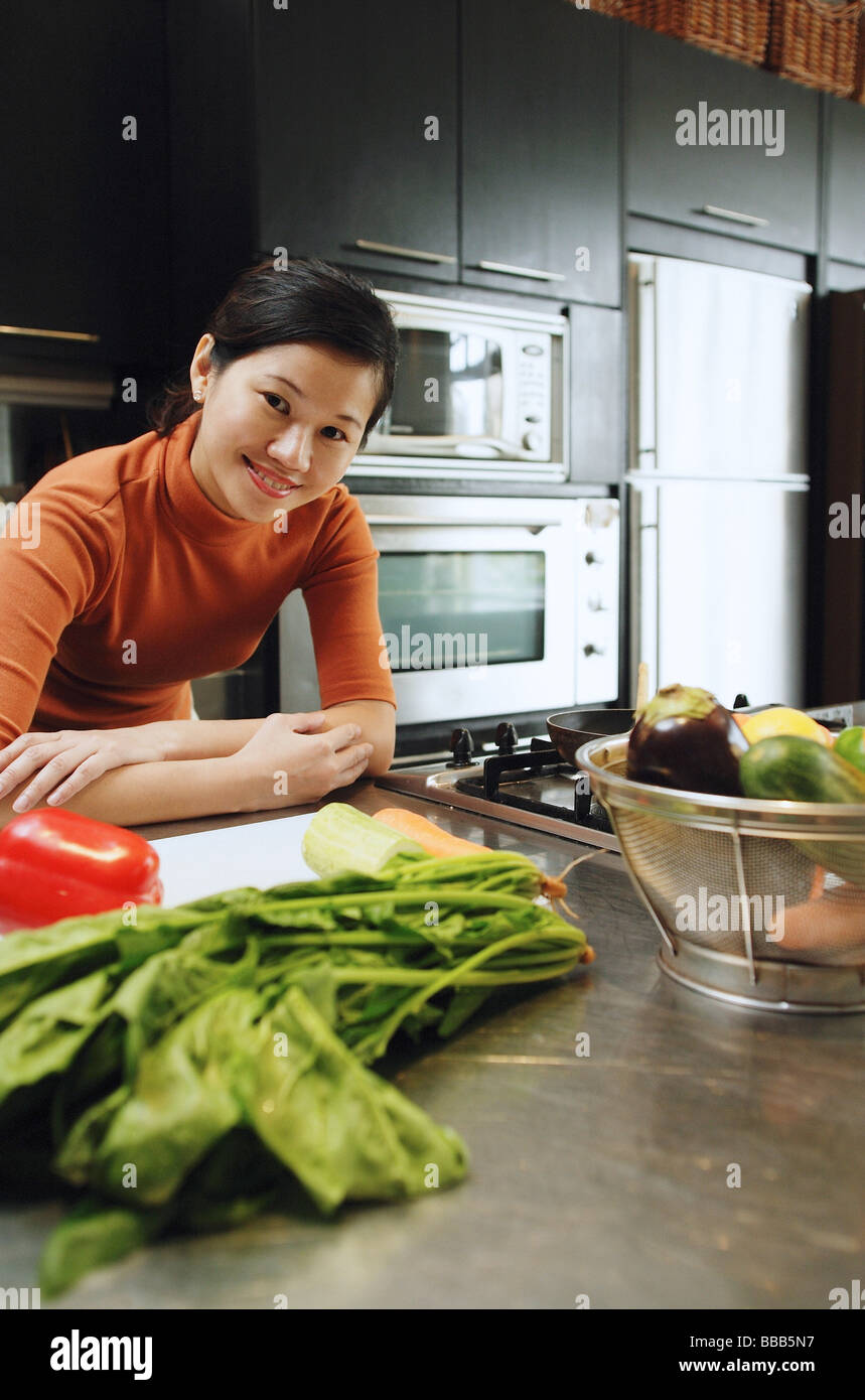 Woman in kitchen, leaning on kitchen counter, looking at camera Stock ...