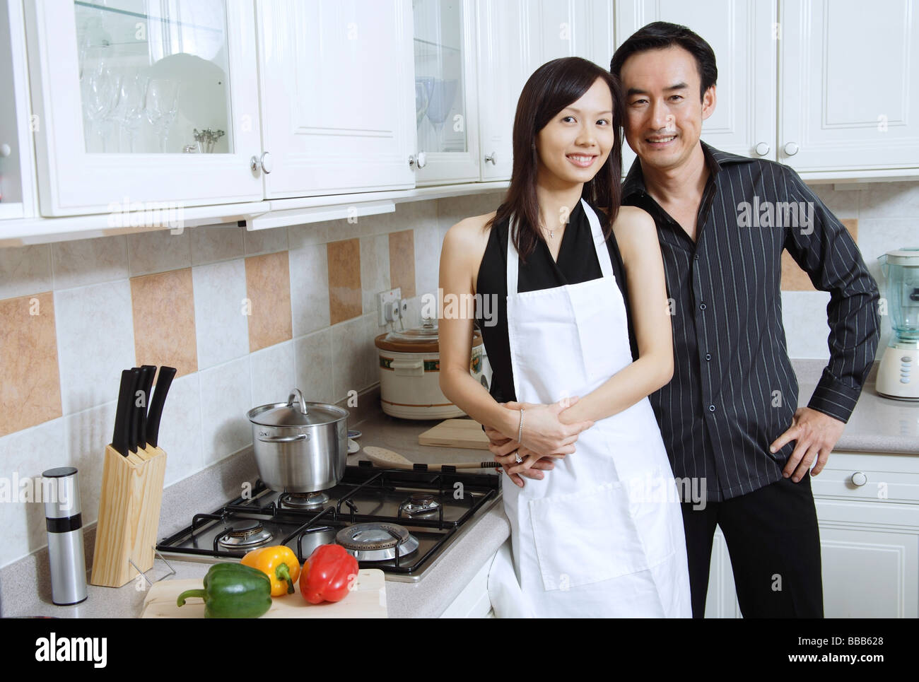 Couple standing in kitchen, smiling at camera Stock Photo - Alamy