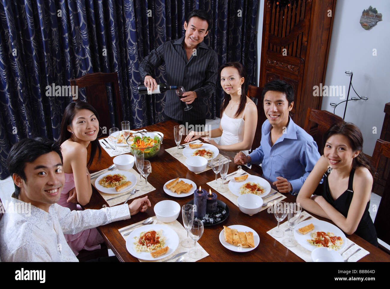 Adults at a dinner party, sitting around table, smiling at camera Stock ...