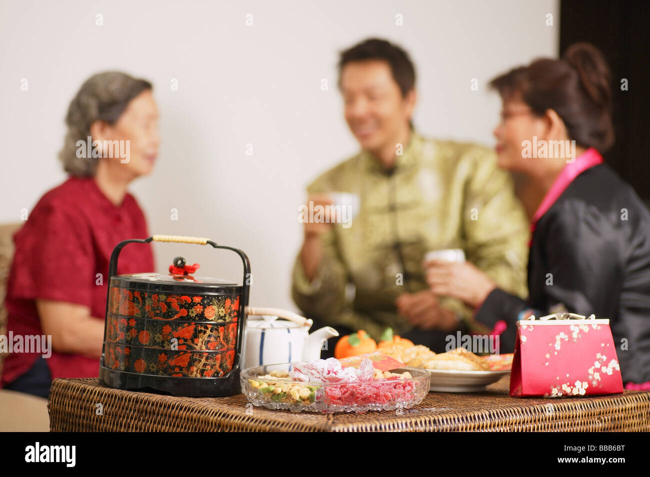 People having tea in living room, traditional Chinese New Year goodies ...
