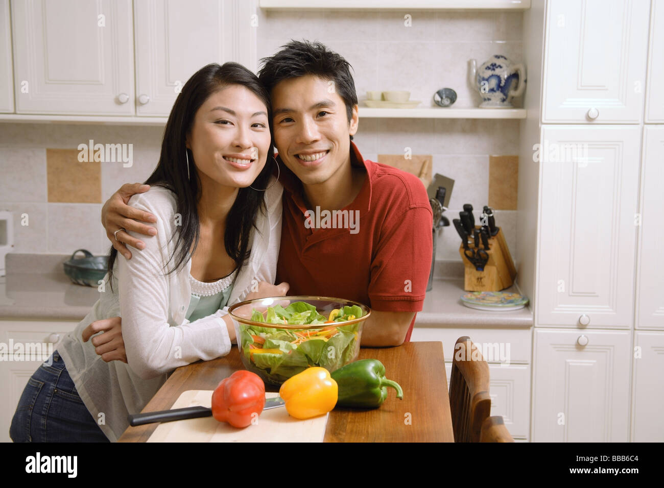 Couple leaning on kitchen counter, smiling at camera Stock Photo - Alamy