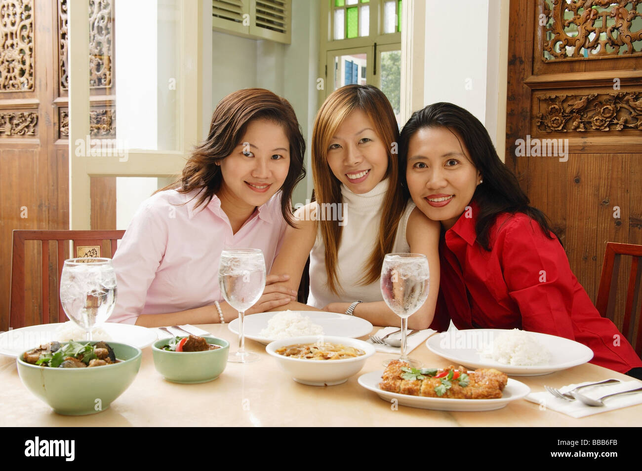 Three women sitting at restaurant table, smiling at camera Stock Photo ...