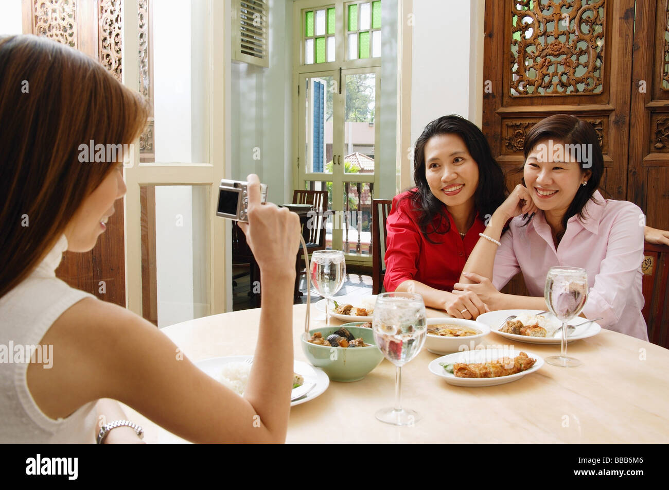 Woman taking pictures of friends, holding camera Stock Photo - Alamy