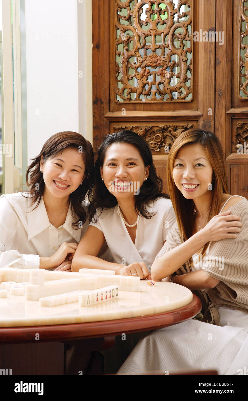 Three women sitting side by side, smiling Stock Photo - Alamy