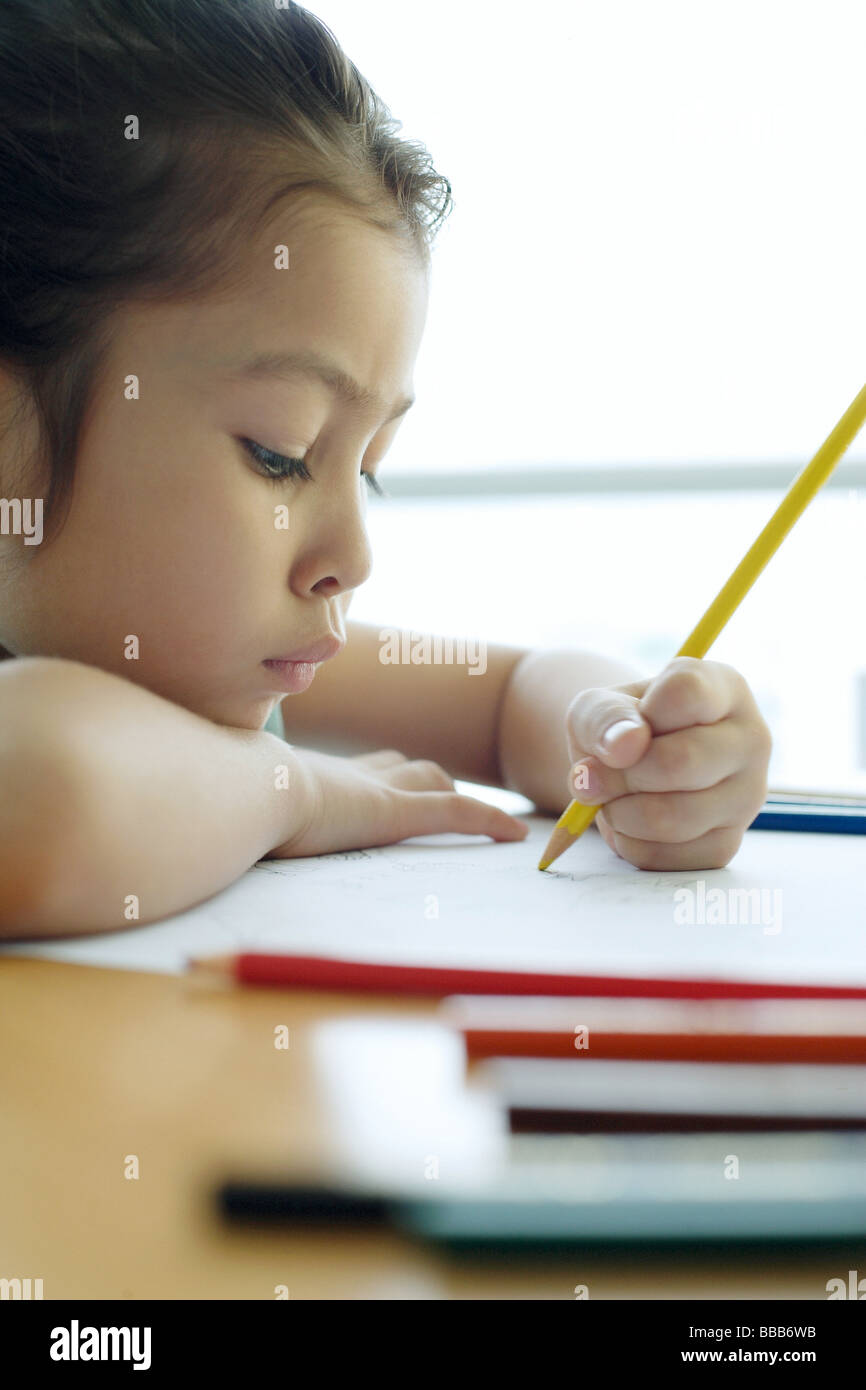 Young girl drawing, resting chin on arm, sideview Stock Photo - Alamy