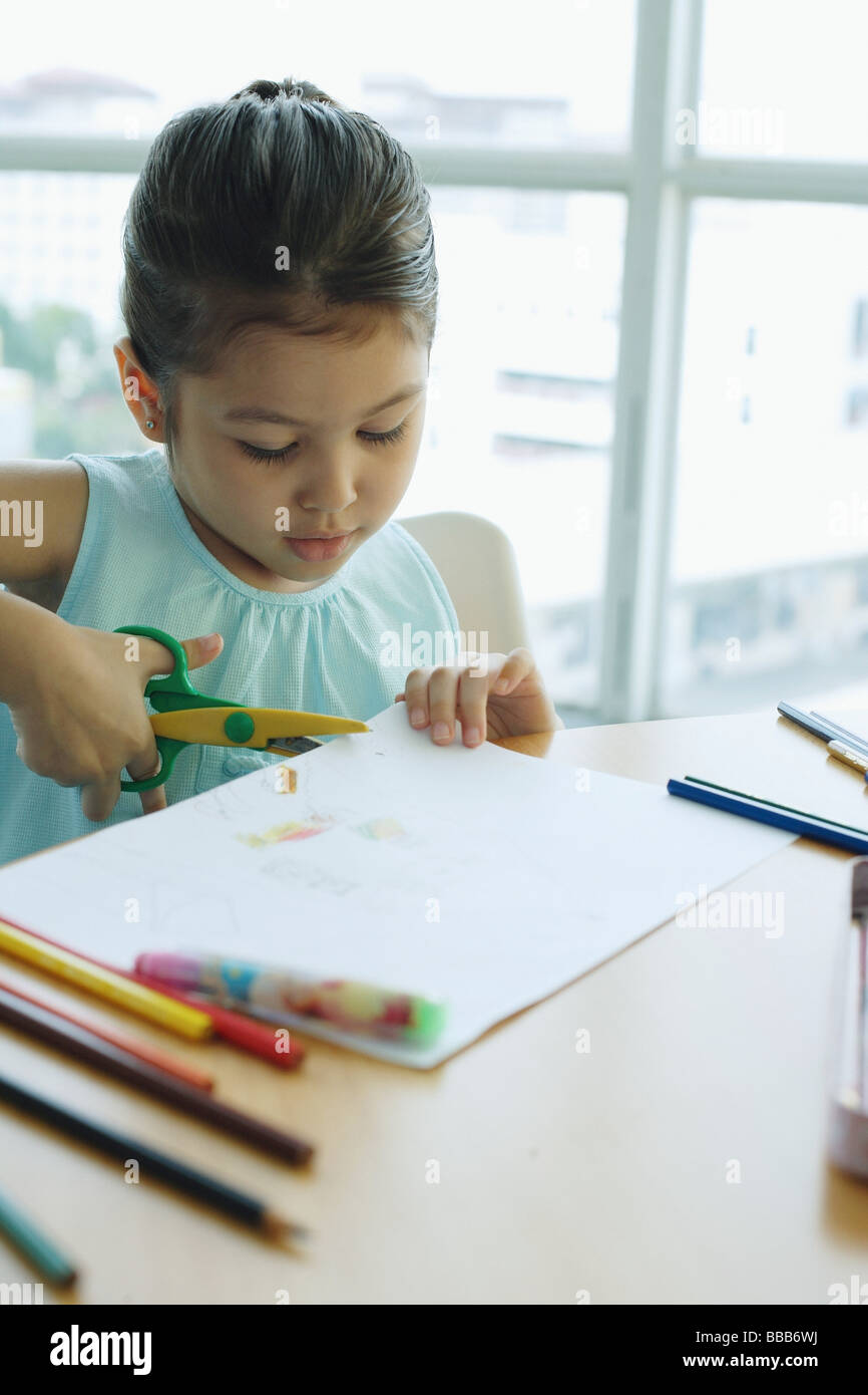 Young girl holding scissors, cutting paper Stock Photo - Alamy