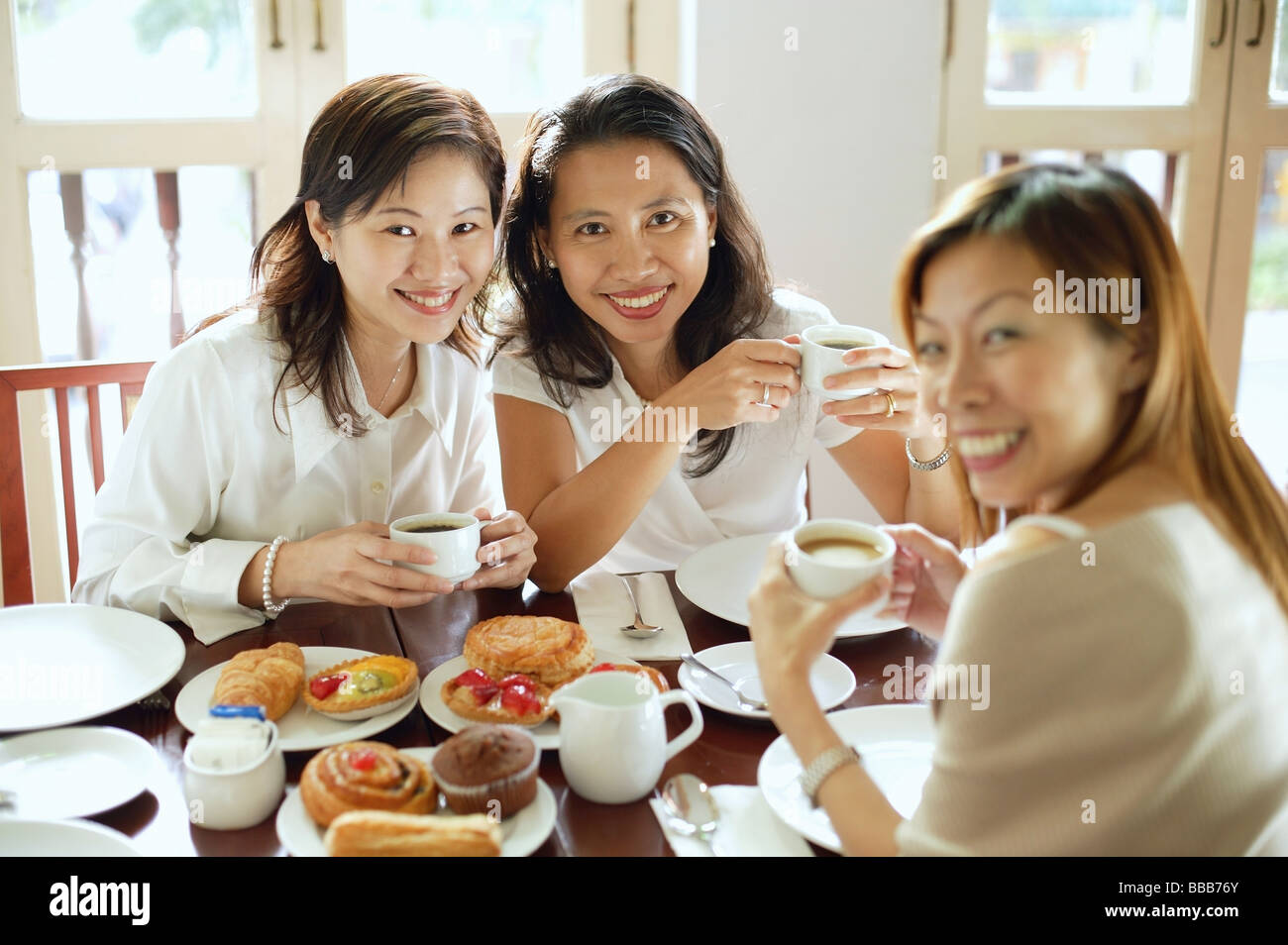 Three women having tea at cafe, smiling at camera Stock Photo - Alamy